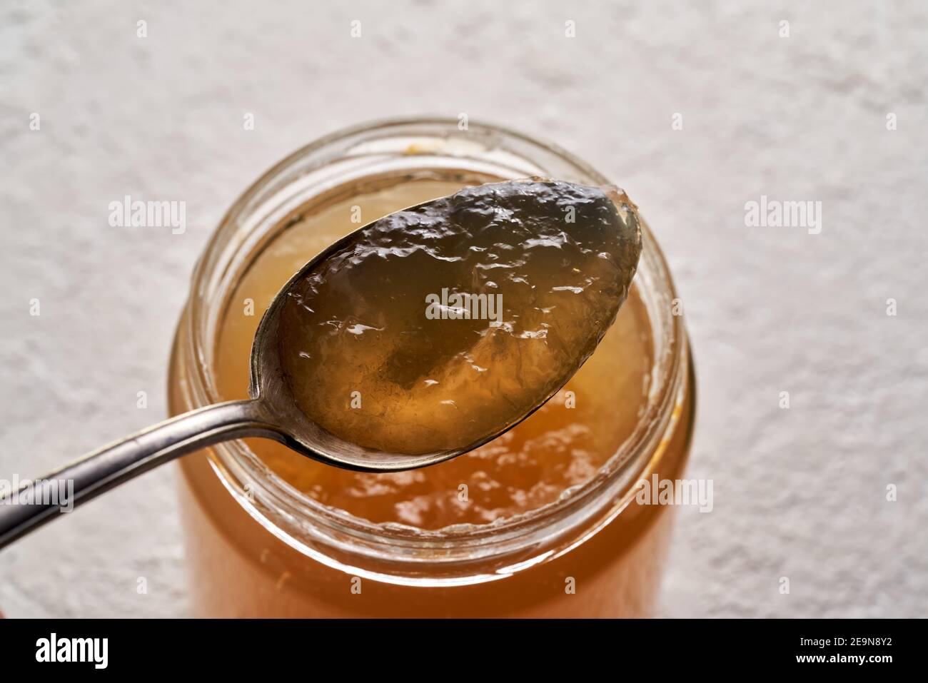 Cold congealed beef bone broth on a spoon over a glass jar Stock Photo ...