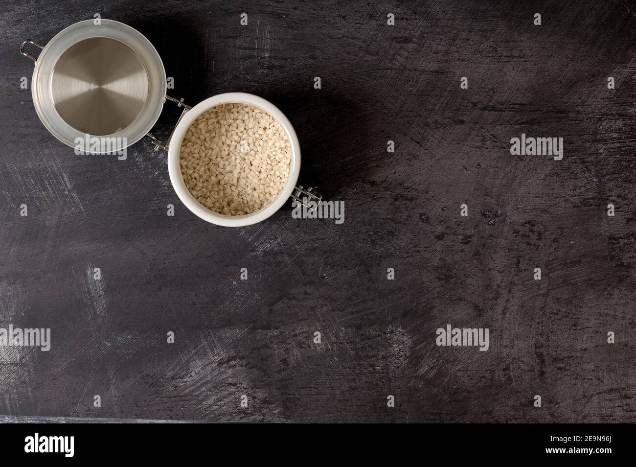 detail of a white ceramic jar with a lid with rice inside on a dark ...