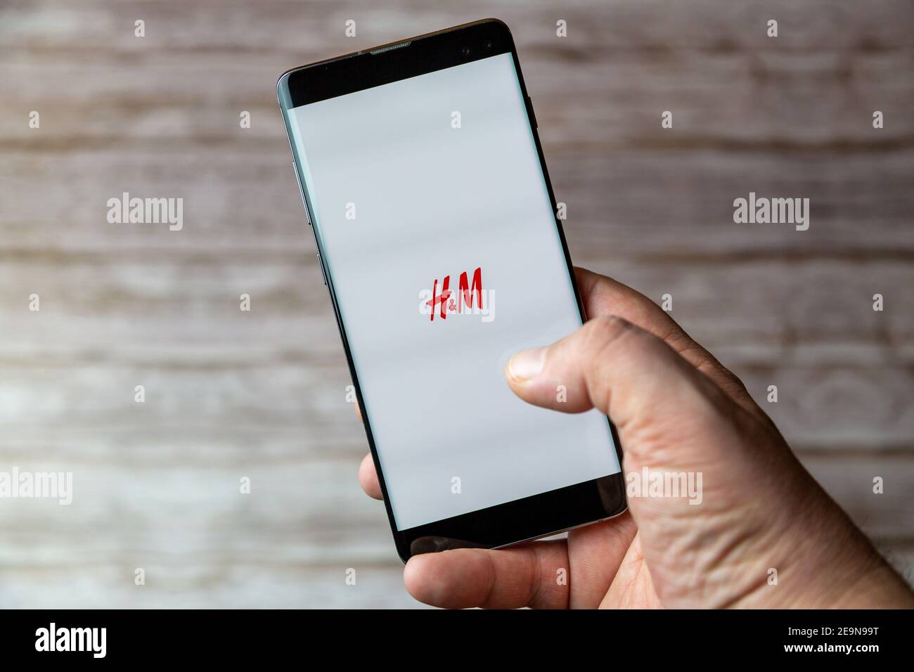 A Mobile phone or cell phone being held showing the H&M app open on ...