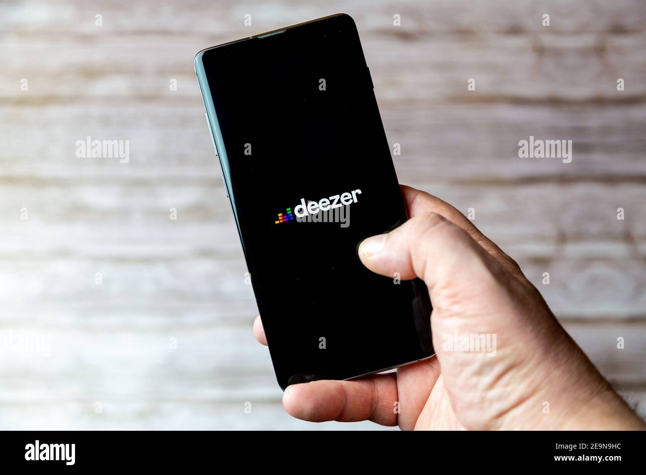 A Mobile phone or cell phone being held showing the deezer music app ...