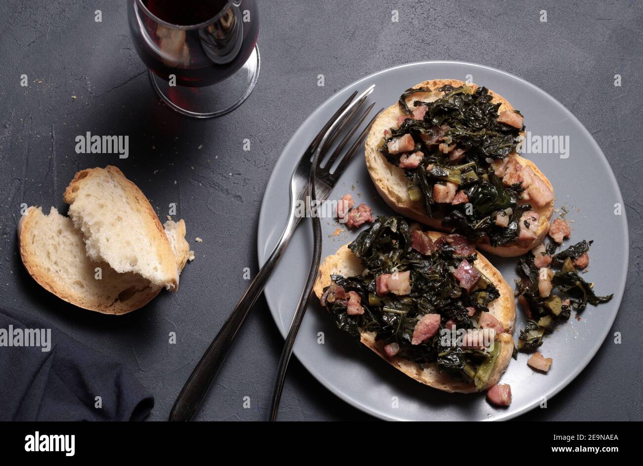 Tuscan black cabbage bruschetta and a glass of wine on grey background ...