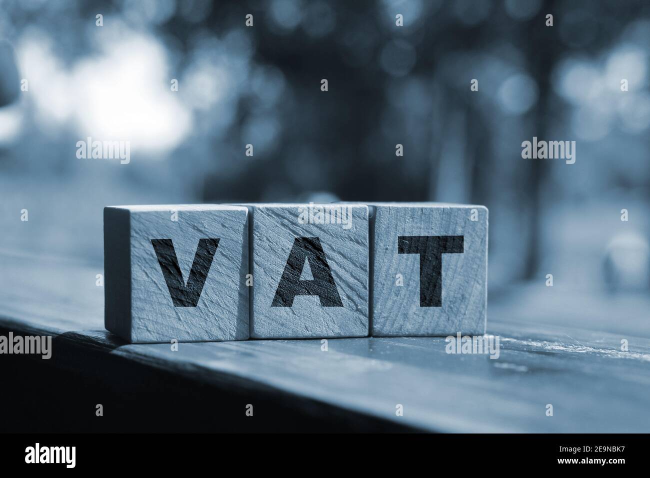 Vat abbreviation letters on wooden cubes over blur background with copy ...
