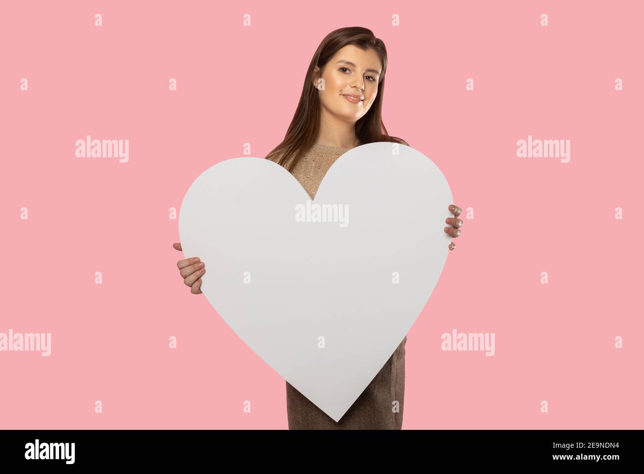 A beautiful girl in love holds a heart shape in her hand. Young woman ...