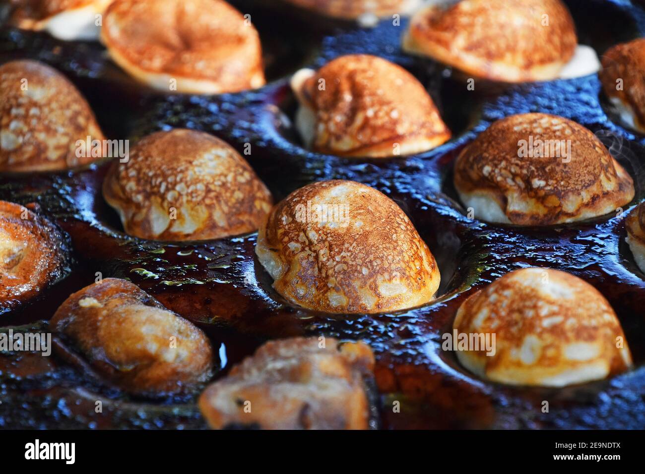 Close up of cooking small round Dutch traditional sweet pancakes, high ...