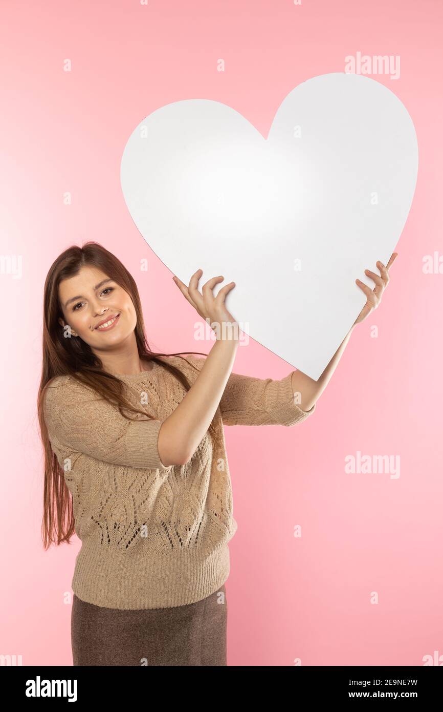 A beautiful girl in love holds a heart shape in her hand. Young woman ...