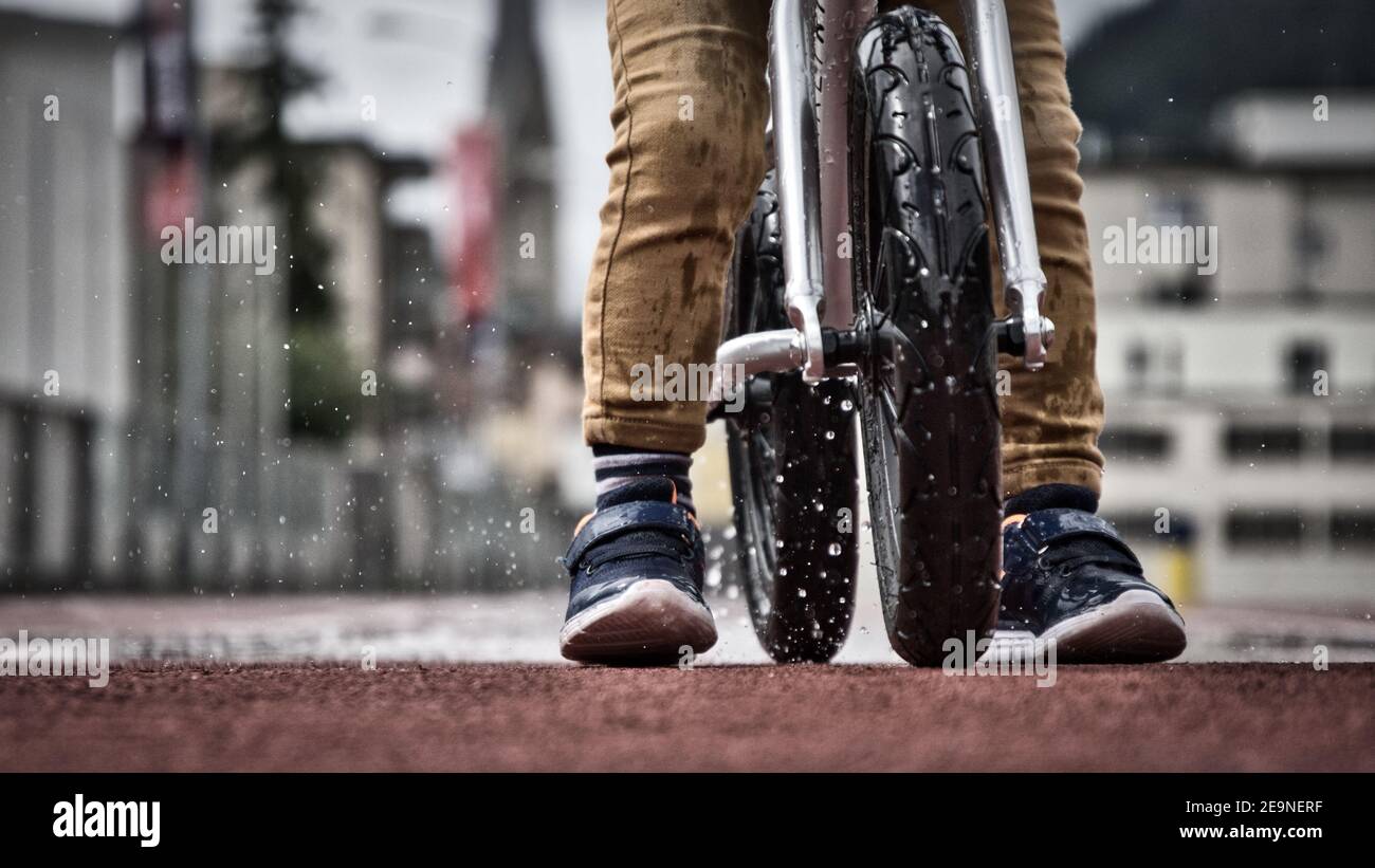 child has fun with the balance bike, happy child plays with a puddle of water, cycling at a ...