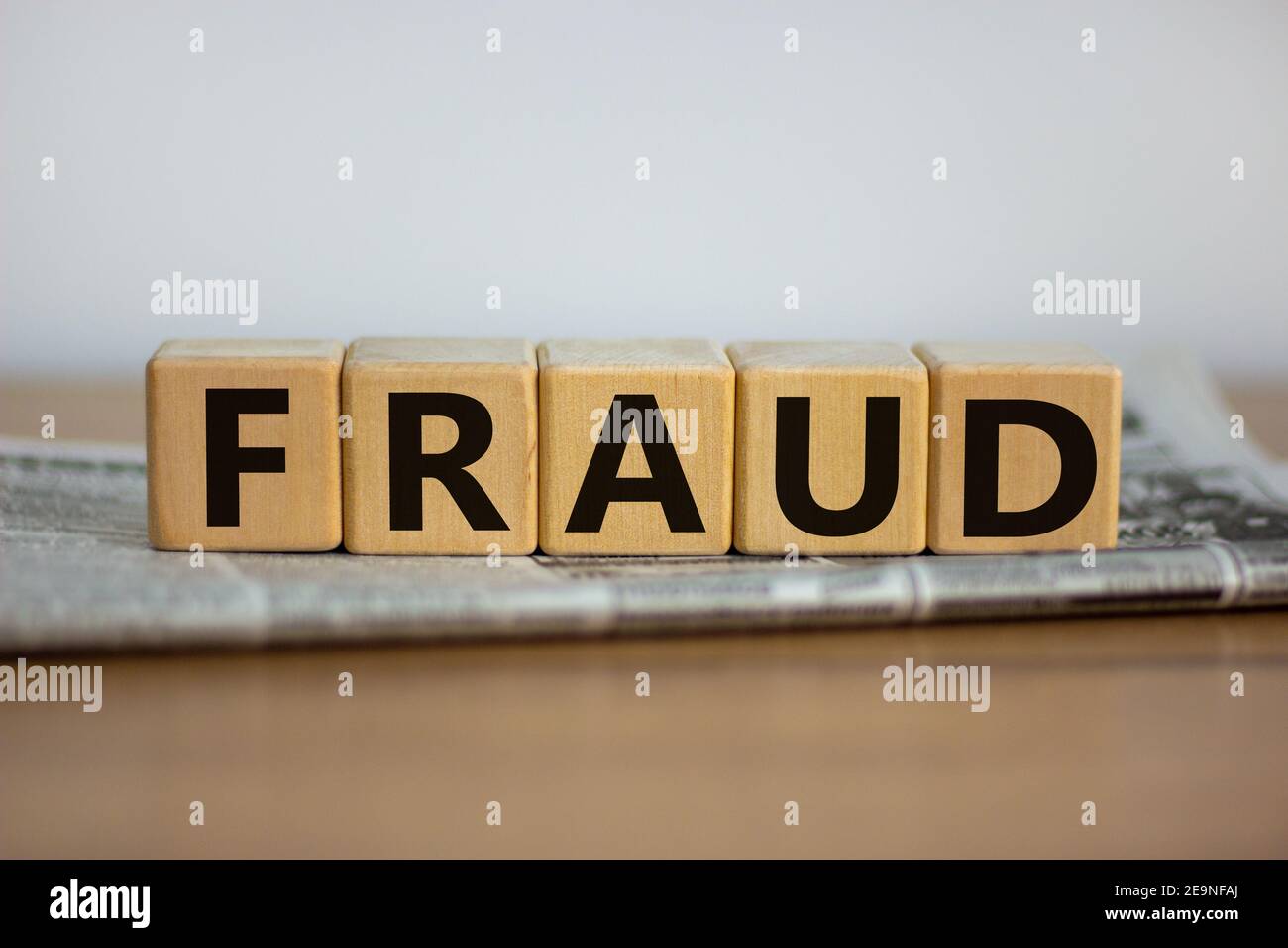 Fraud symbol. Wooden cubes placed on a newspaper. The word 'fraud ...