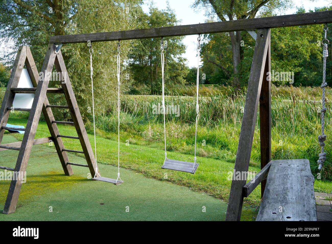 Wooden swings and slide captured in a grass-covered park Stock Photo ...