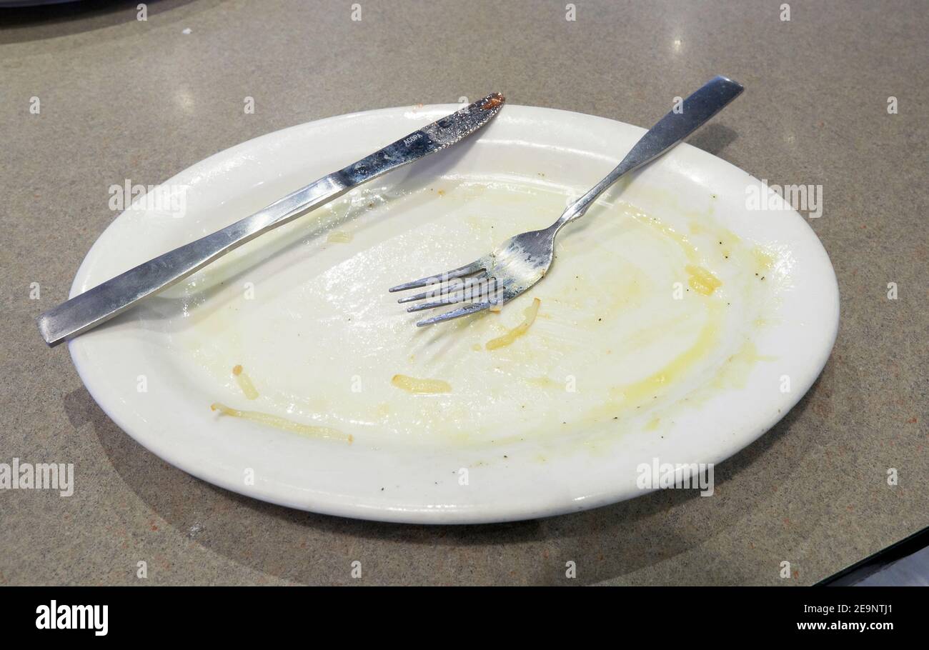 Dirty empty plate with knife and fork after breakfast meal of eggs in a ...