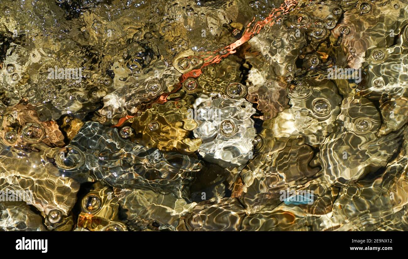 High angle shot of the rocks in the river visible through the clear ...