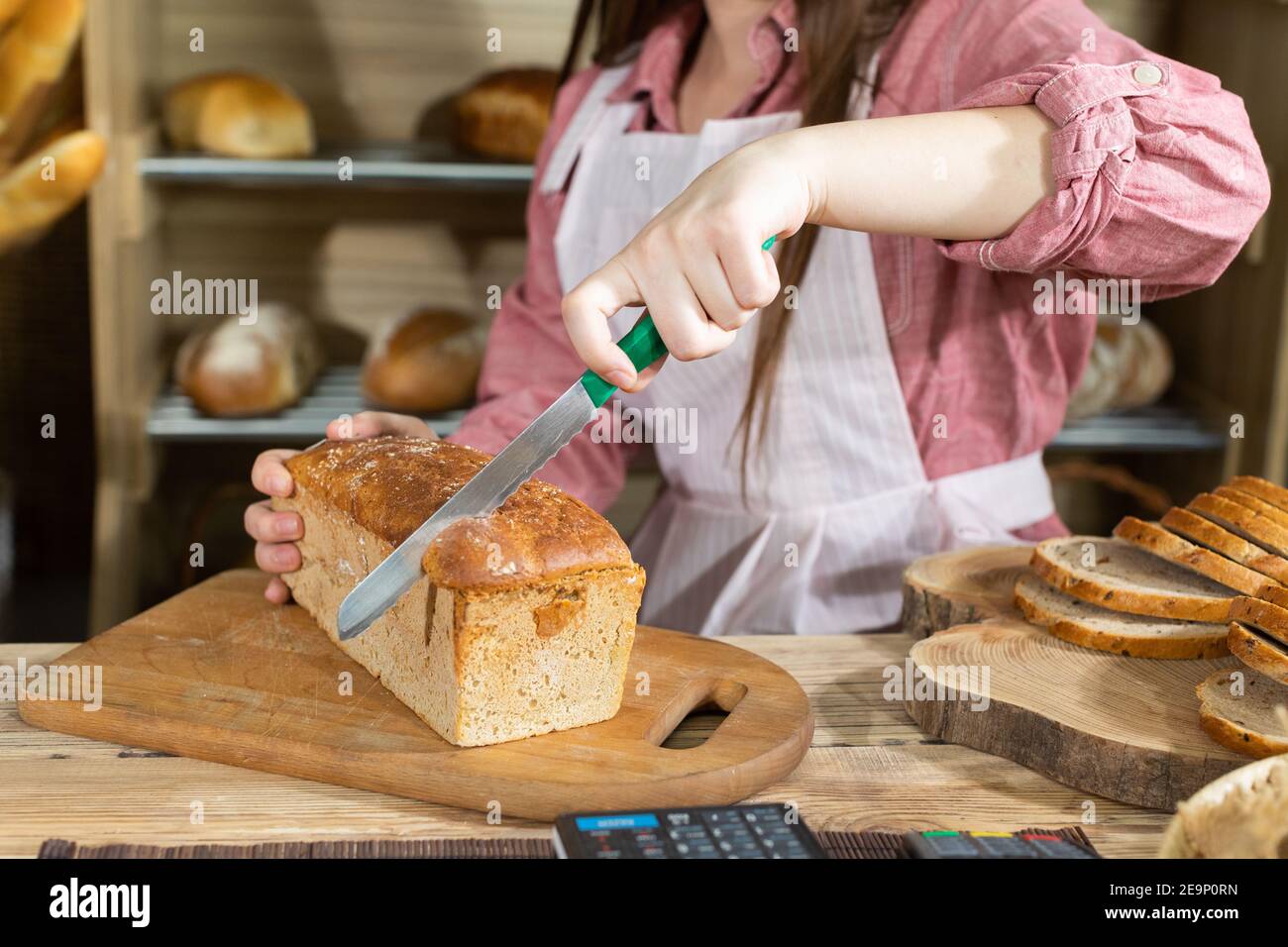 Up close, you can see a young girl starting to cut a loaf of bread with ...