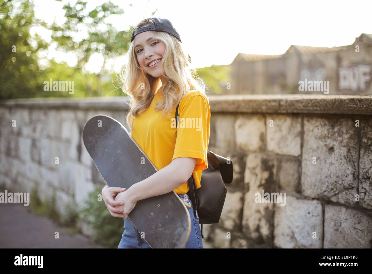 Shallow focus of a young smiling blonde woman with a skateboard posing ... Shallow focus of a young smiling blonde woman with a skateboard posing ...