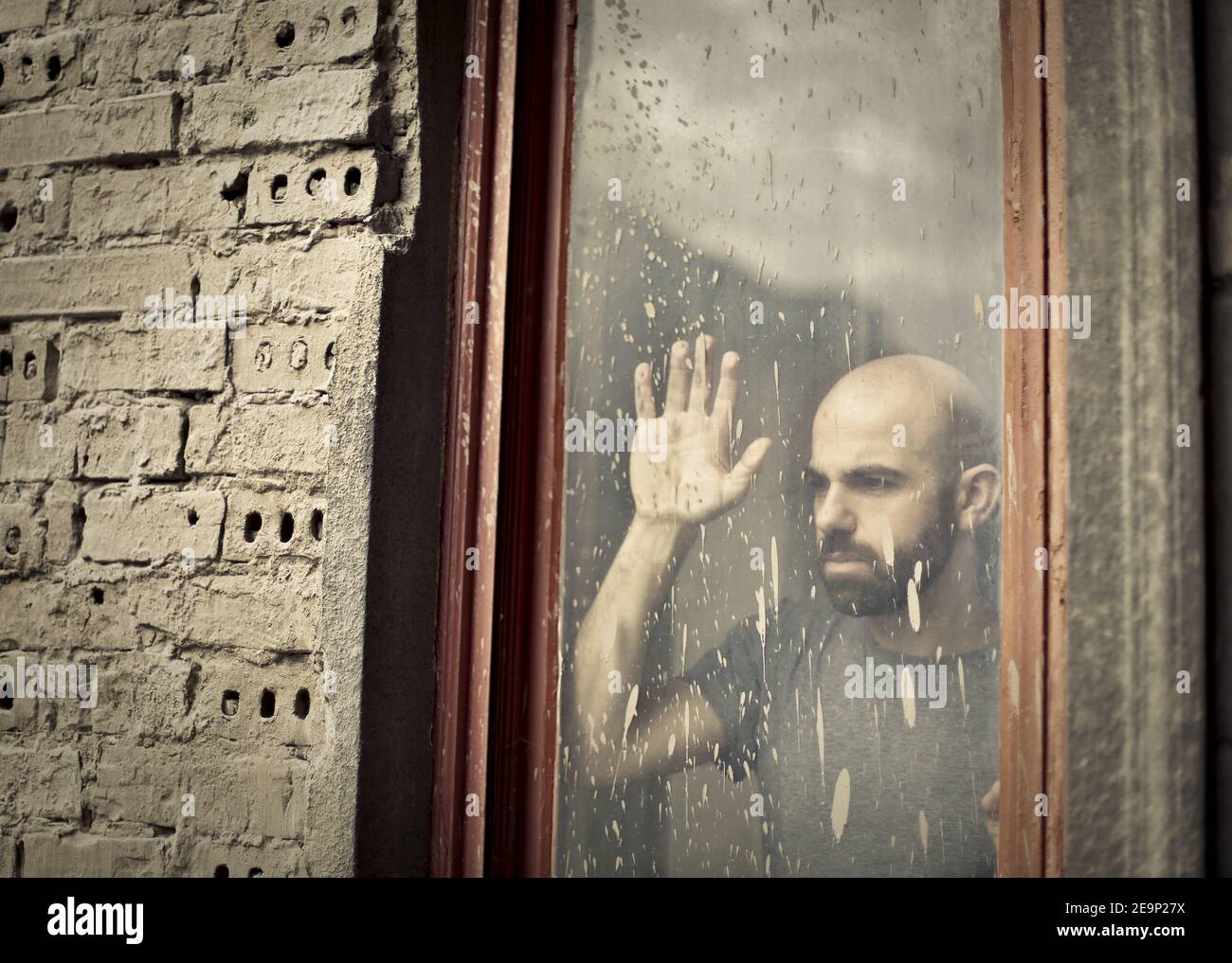 Adult lonely depressed man looking out of the window on a gloomy day ...