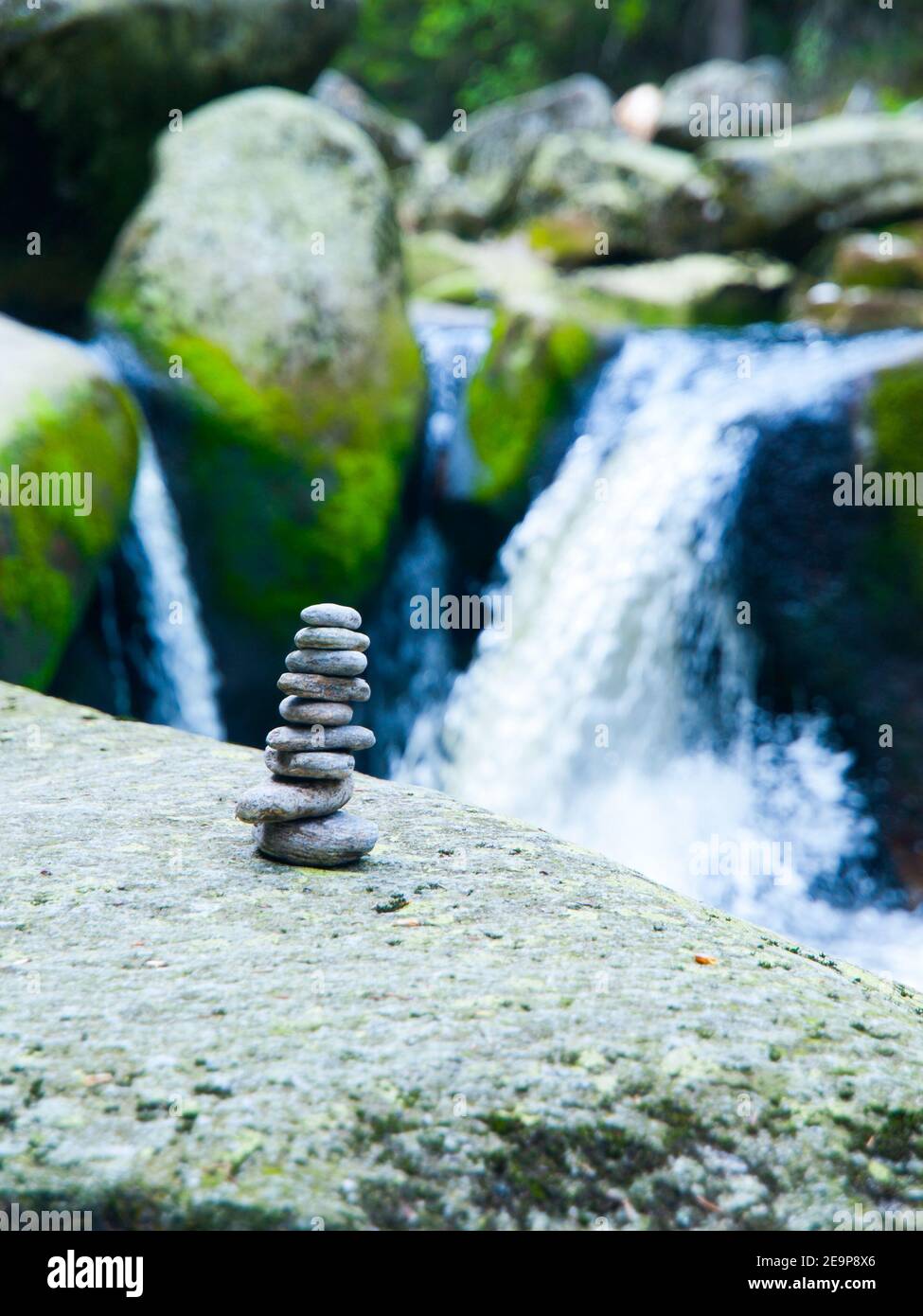 Balanced pebble stone pyramid with unfocused river waterfall on ...