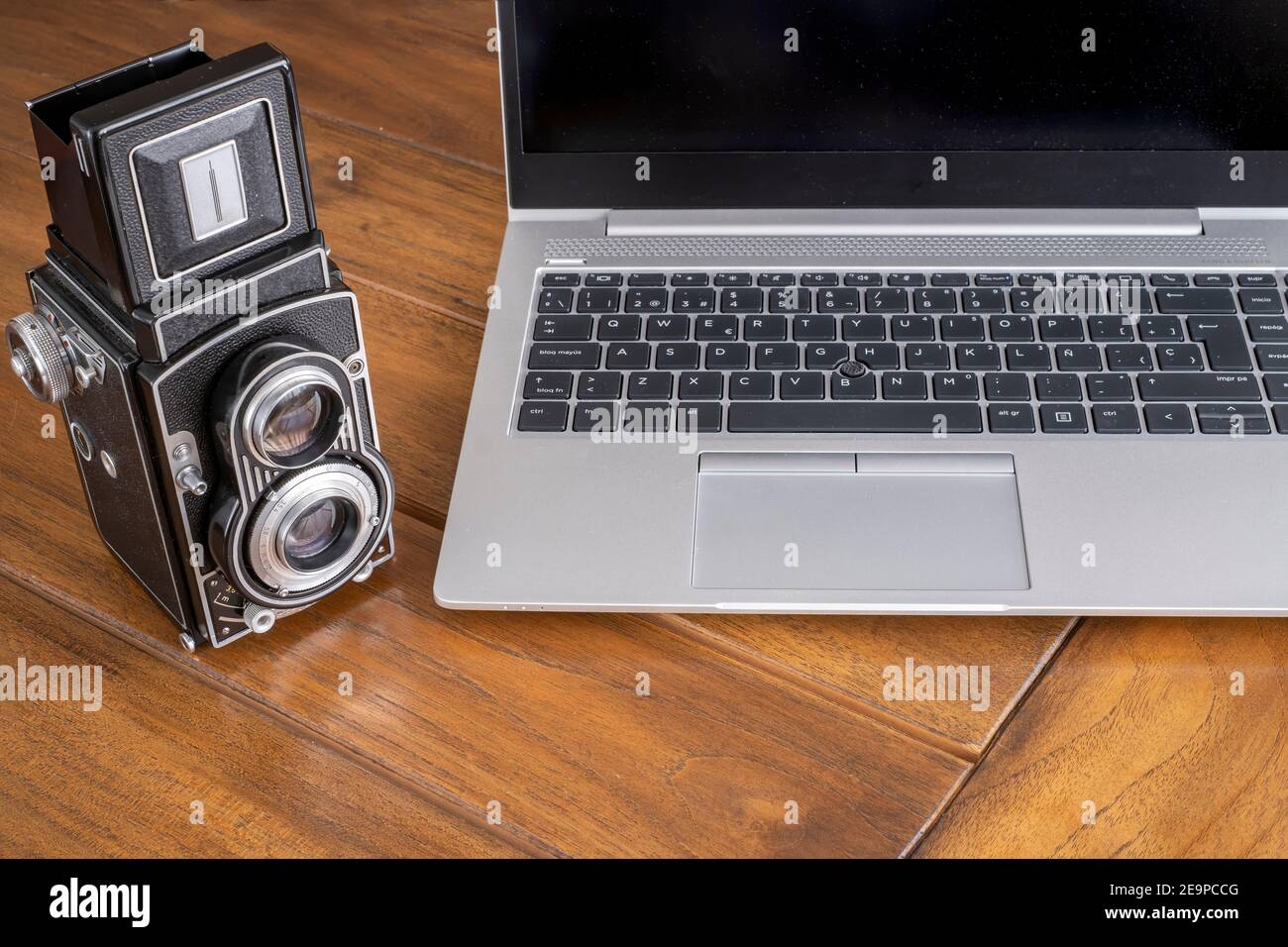 a modern laptop computer next to an antique twin lens camera ...