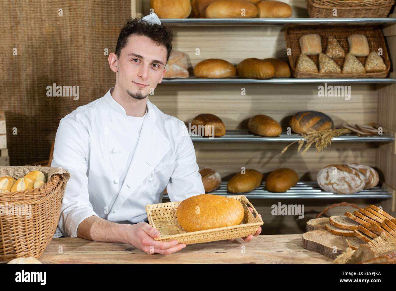 A clerk sits behind the counter serving his own baked goods. A handsome ...
