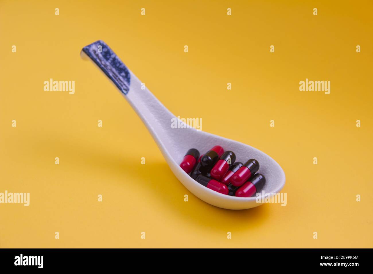 Pharmaceutical medicine pills on porcelain spoon with isolated yellow ...