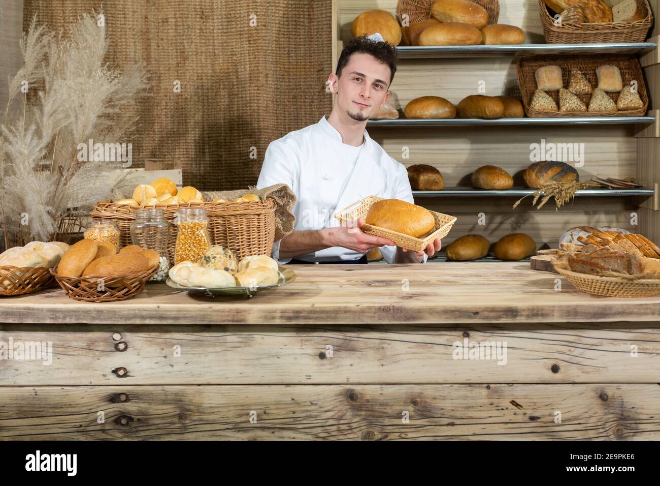 A clerk sits behind the counter serving his own baked goods. A handsome ...
