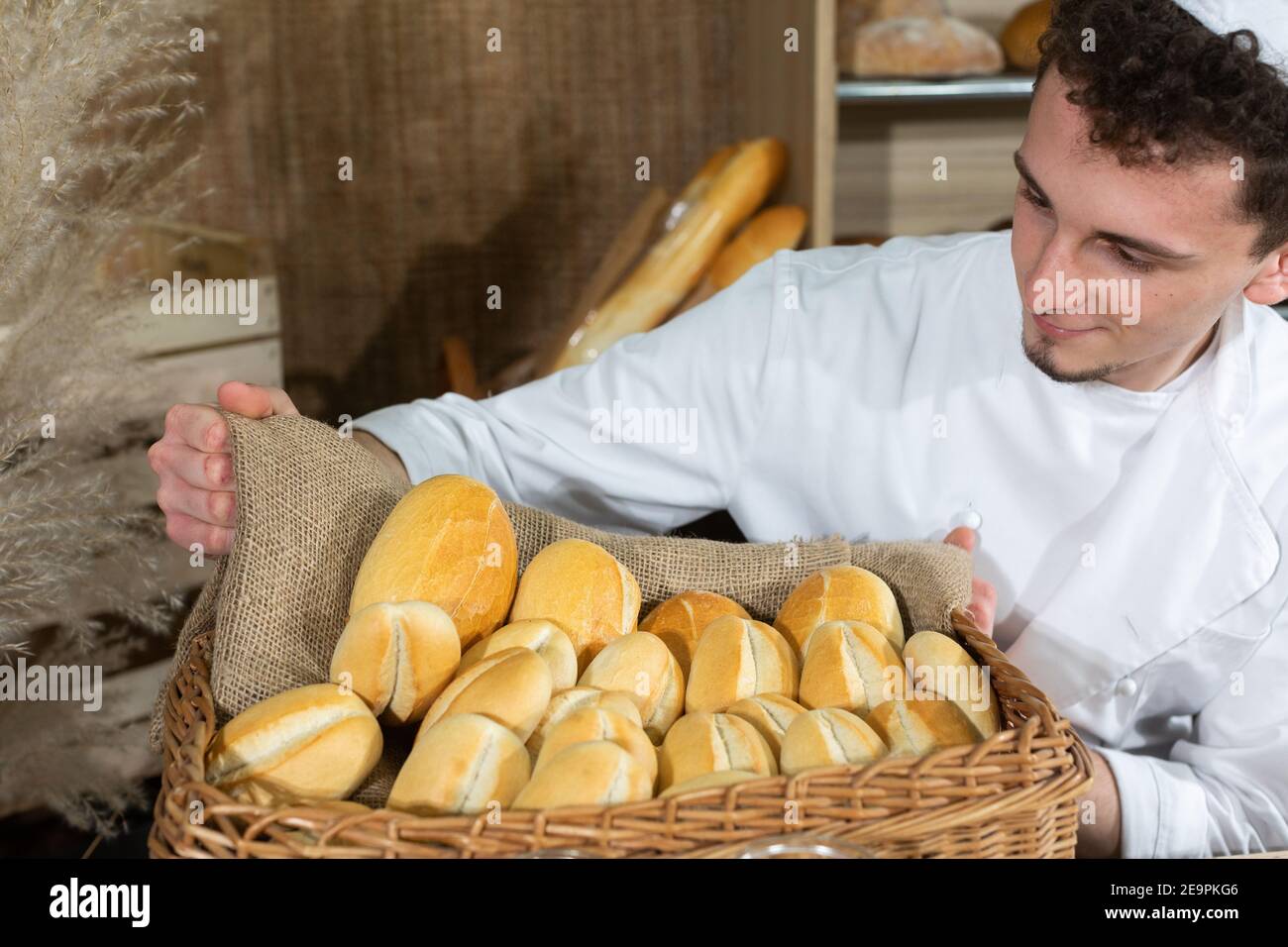 A clerk sits behind the counter serving his own baked goods. A handsome ...