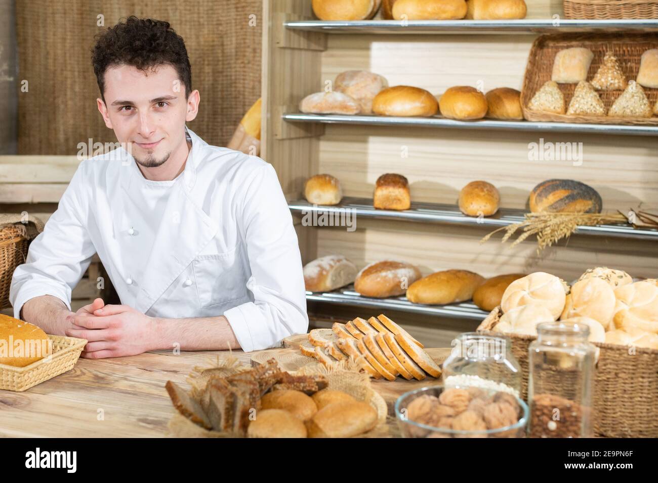 A clerk sits behind the counter serving his own baked goods. A handsome ...