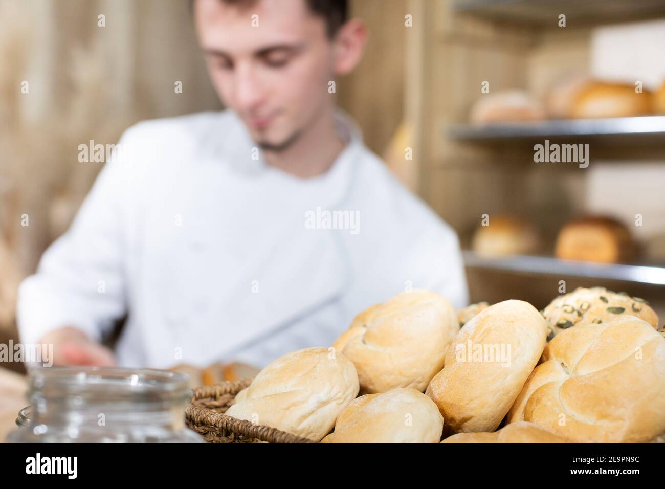 A clerk sits behind the counter serving his own baked goods. A handsome ...