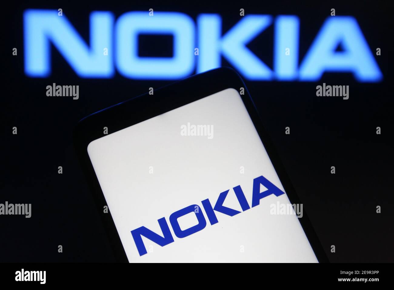 In this photo illustration a Nokia logo is seen on a mobile phone and a ...