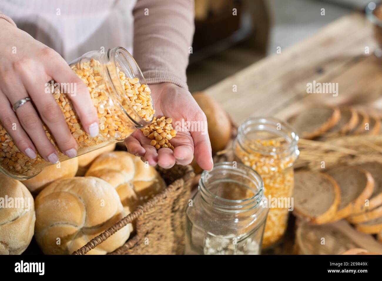 The saleswoman shows the grains of dried corn in the glass container by ...