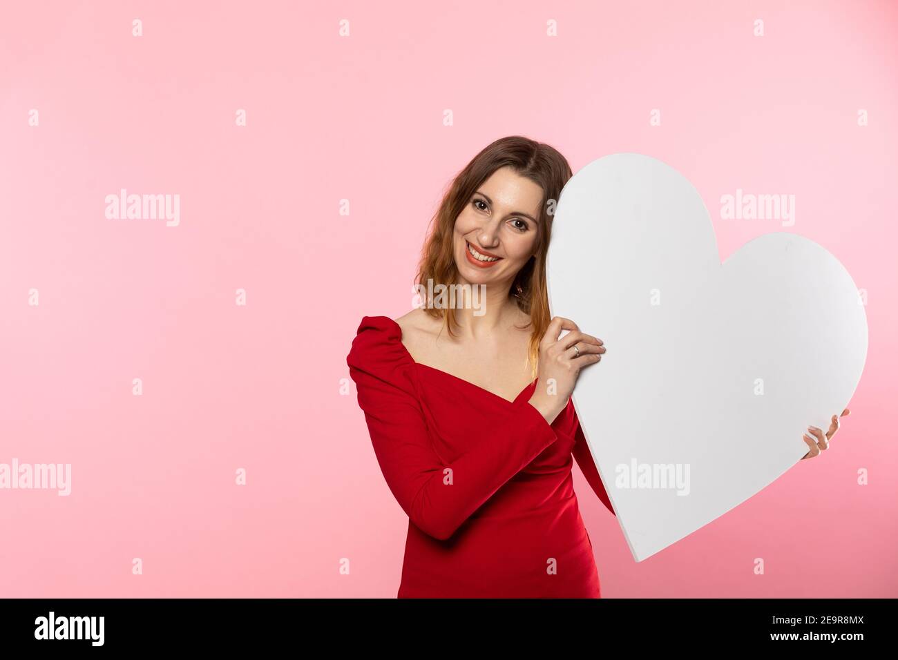 A beautiful girl in love holds a heart shape in her hand. Young woman ...