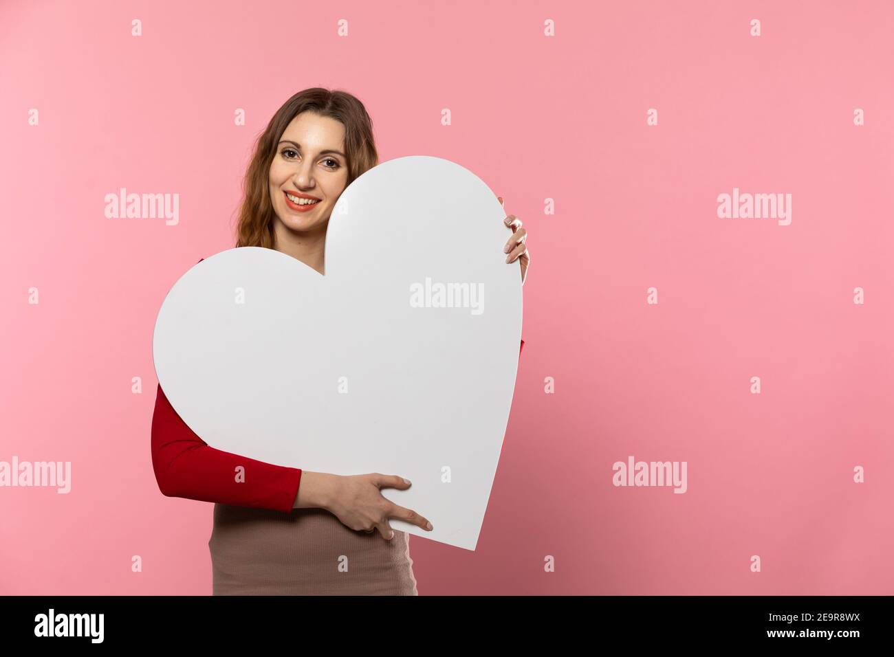 A beautiful girl in love holds a heart shape in her hand. Young woman ...