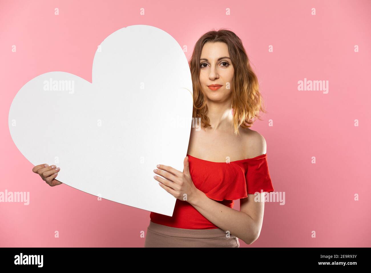 A beautiful girl in love holds a heart shape in her hand. Young woman ...