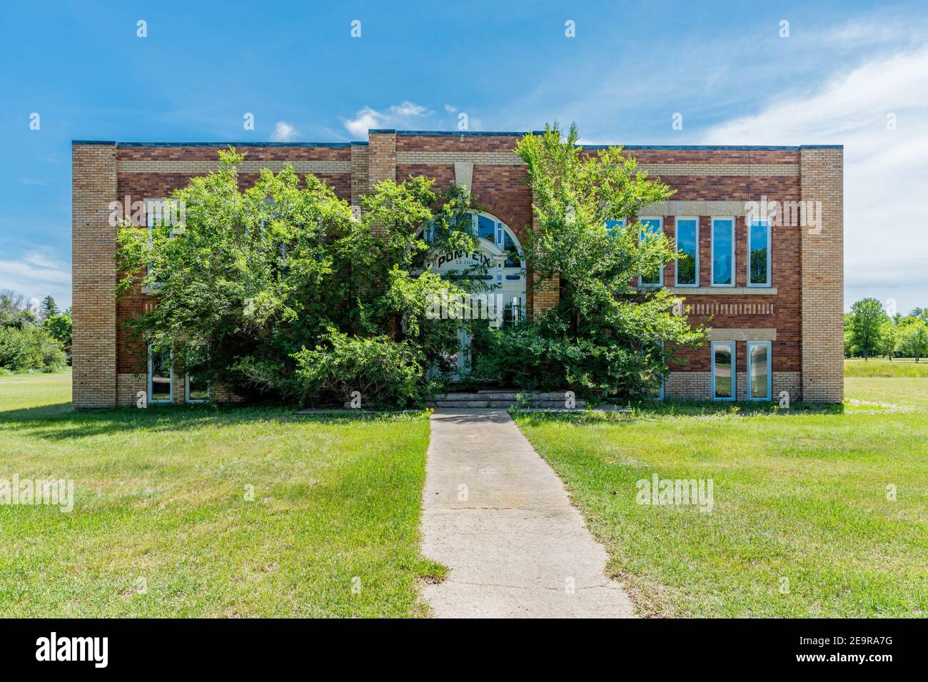 Overgrown plants covering the entrance to the abandoned Ponteix School ...