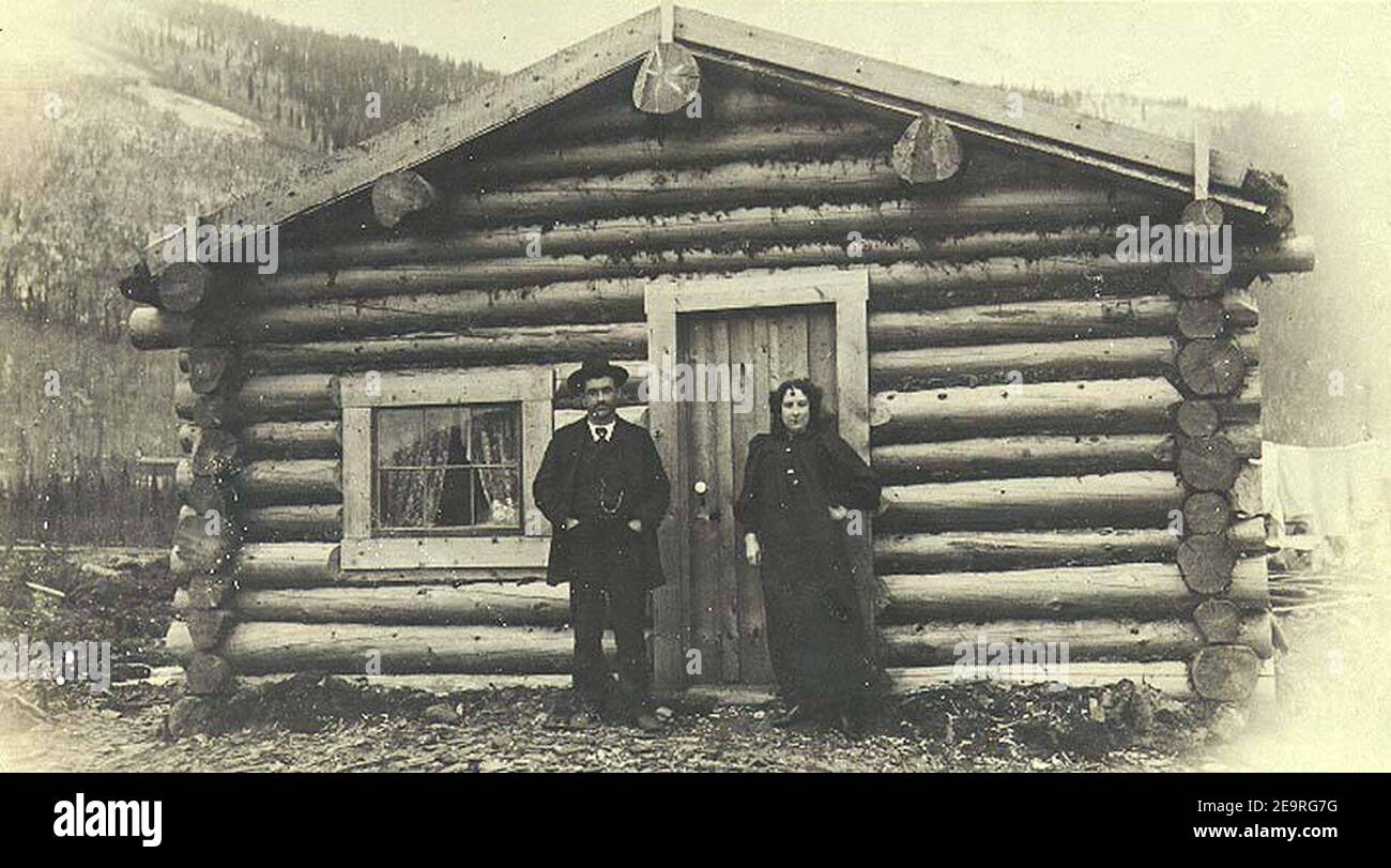 Mr Antone and woman in front of log cabin, Birch Creek, Yukon territory ...
