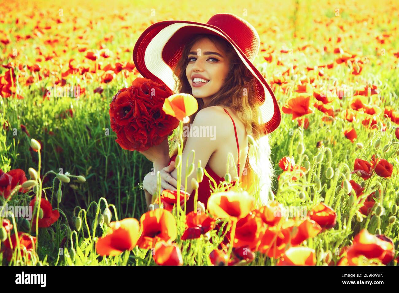 Smiling spring girl. Woman in retro hat hold flower bouquet in field of ...