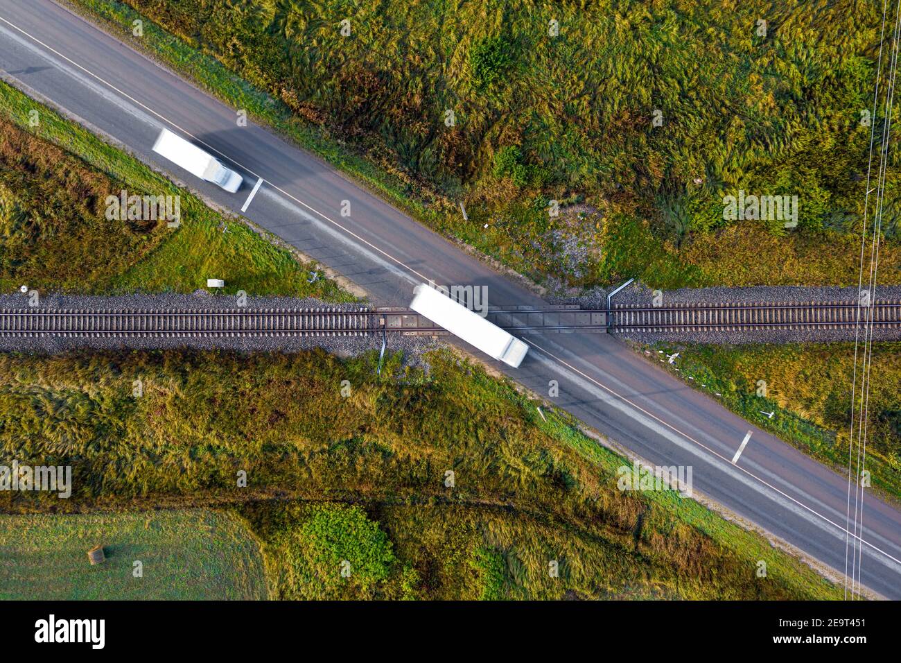 aerial view of railroad tracks crossing a asphalt road with cars in ...