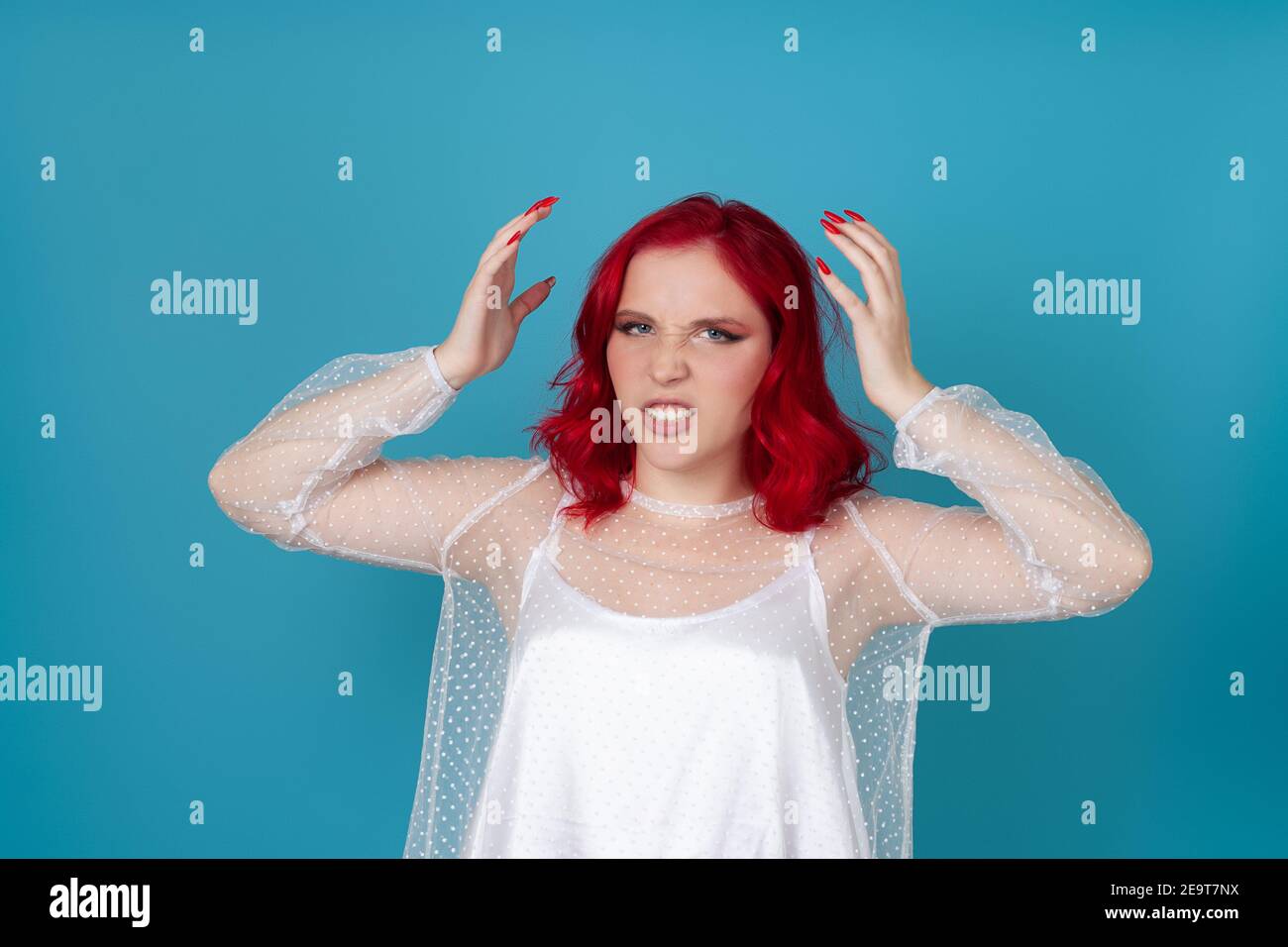 a frustrated, angry woman in white silk dress and with red hair ...