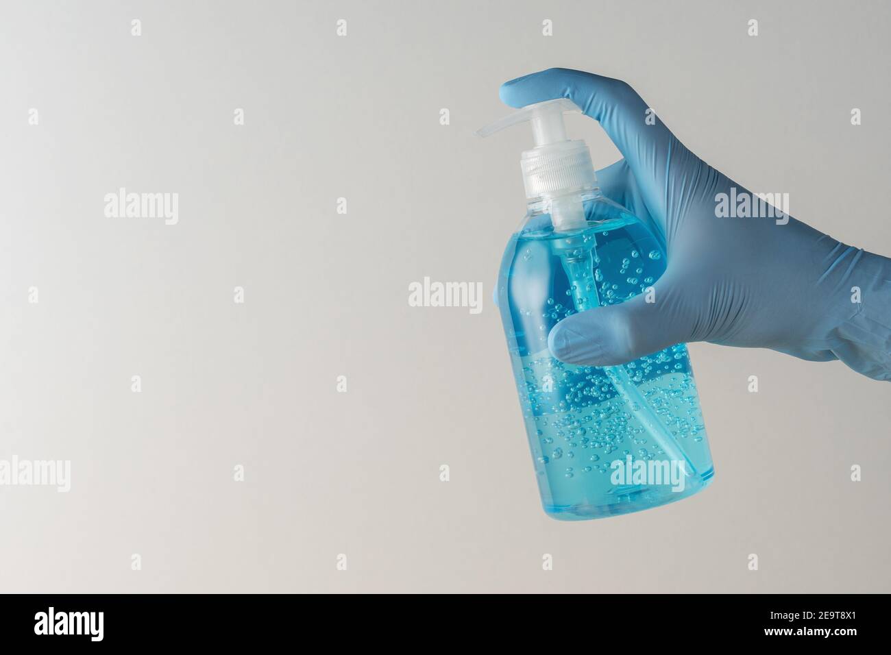Hand in medical glove with hand sanitizer in a bottle on white ...