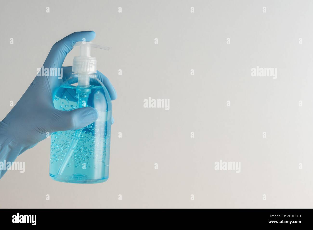 Hand in medical glove with hand sanitizer in a bottle on white ...