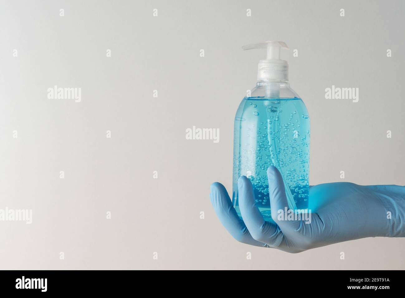 Hand in medical glove with hand sanitizer in a bottle on white ...