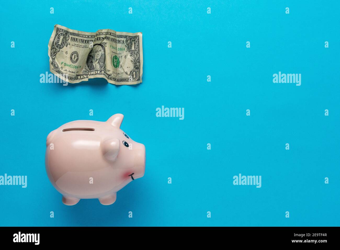 Piggy bank with a crumpled dollar bancnote on blue background . Minimal ...