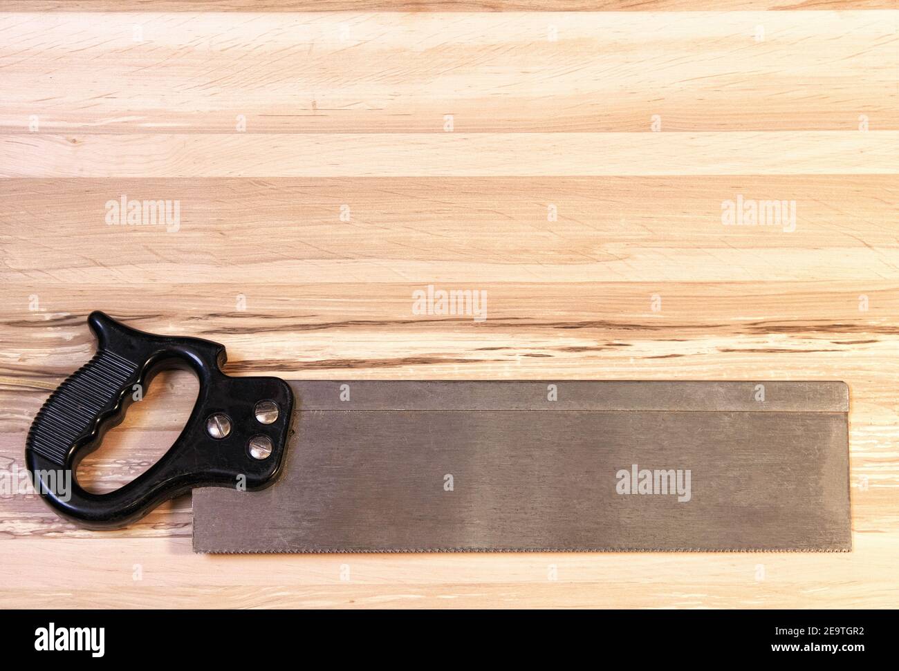 An old carpenter's hacksaw on a furniture alder board. American version ...
