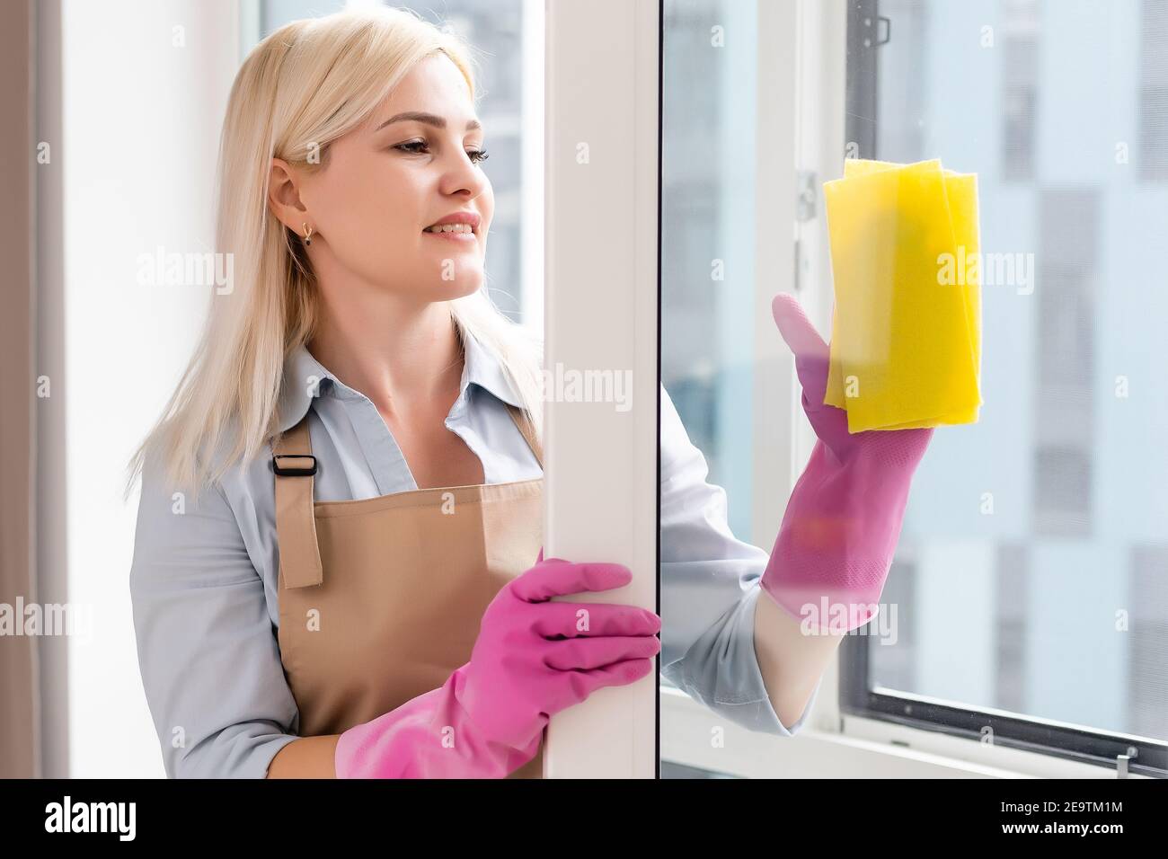 Smiling black woman cleaning windows with glass cleaner Stock Photo - Alamy