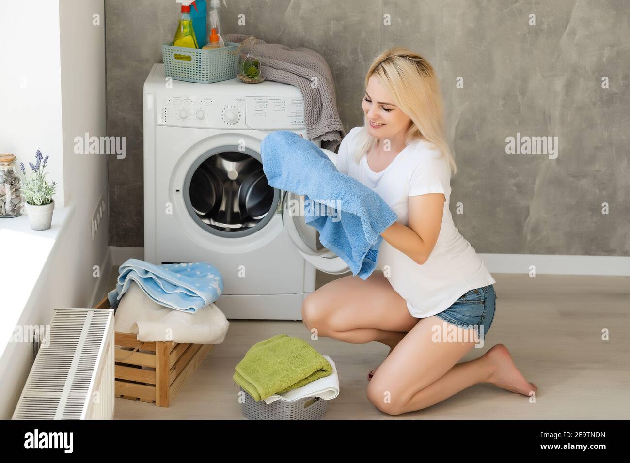 A young housewife with washing machine and clothes. Washing day Stock ...