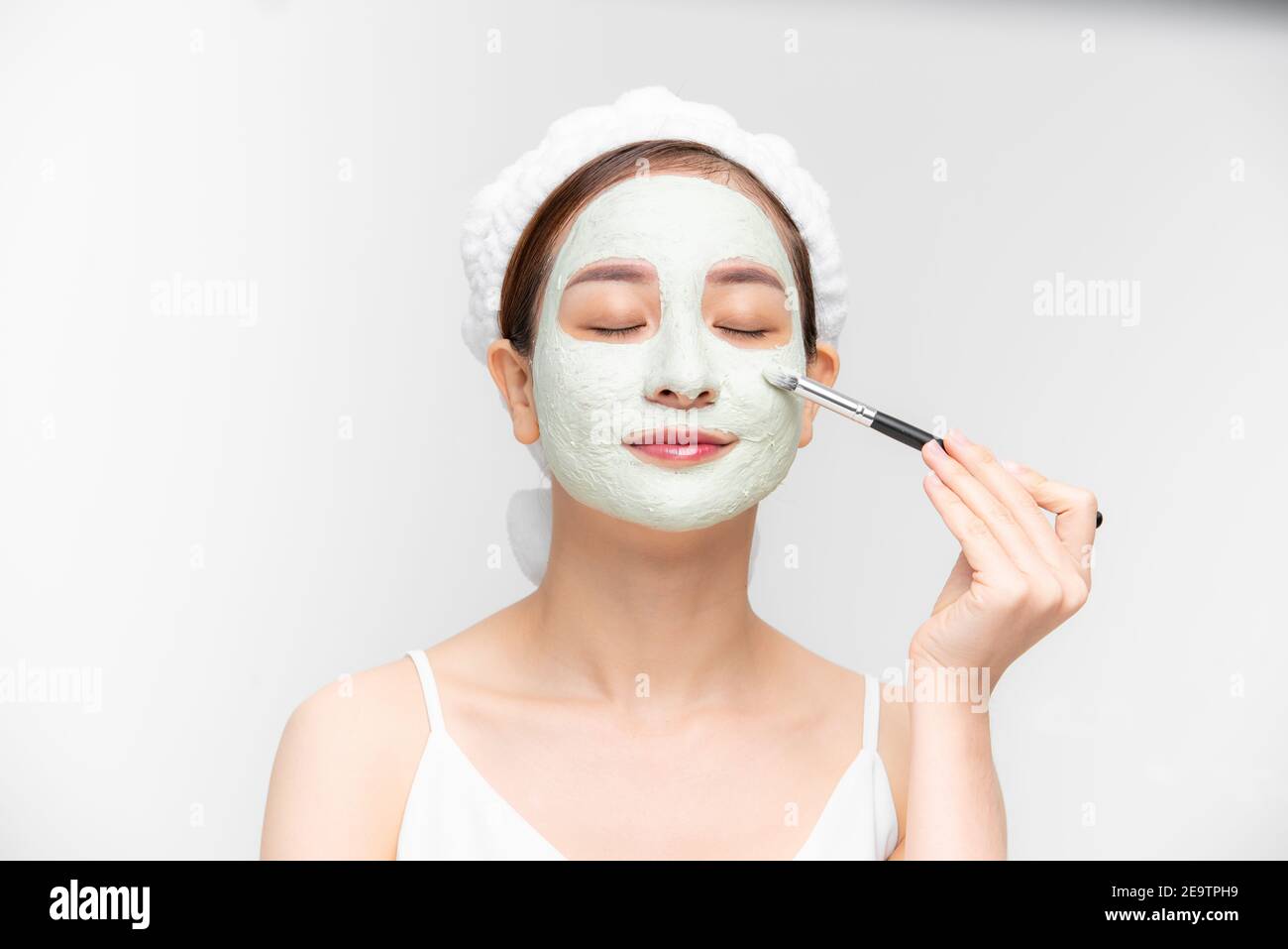 Beautiful Asian woman applying clay mask on her face isolated over ...