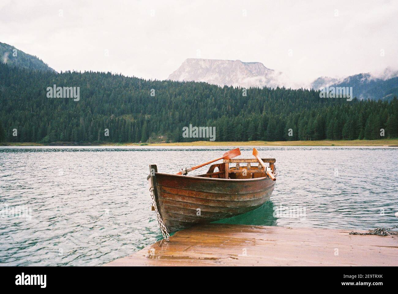 Old wooden boat in a lake with mountains and spruce forest in the ...