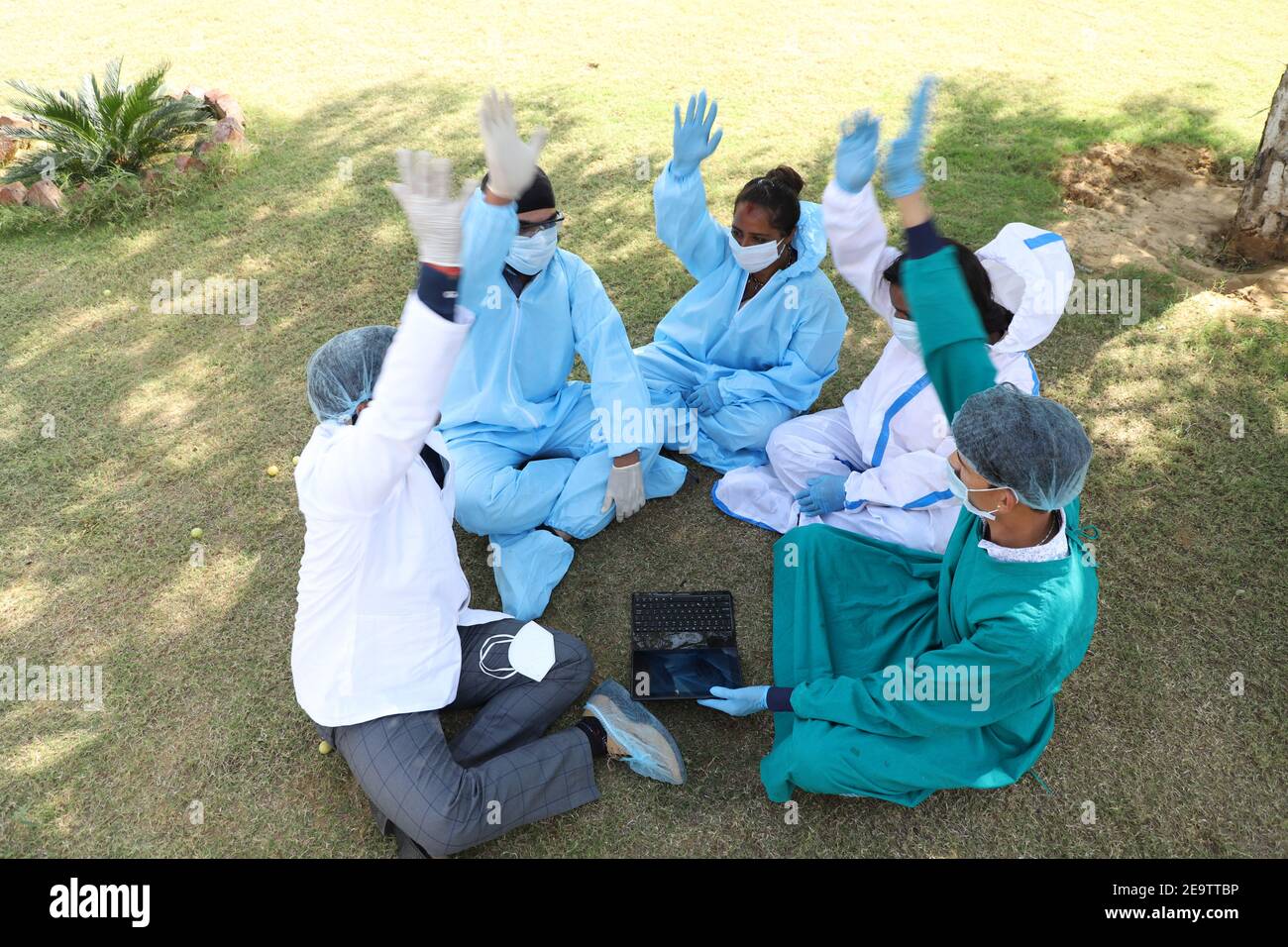 The Indian doctors high fiving each other while sitting on green grass ...