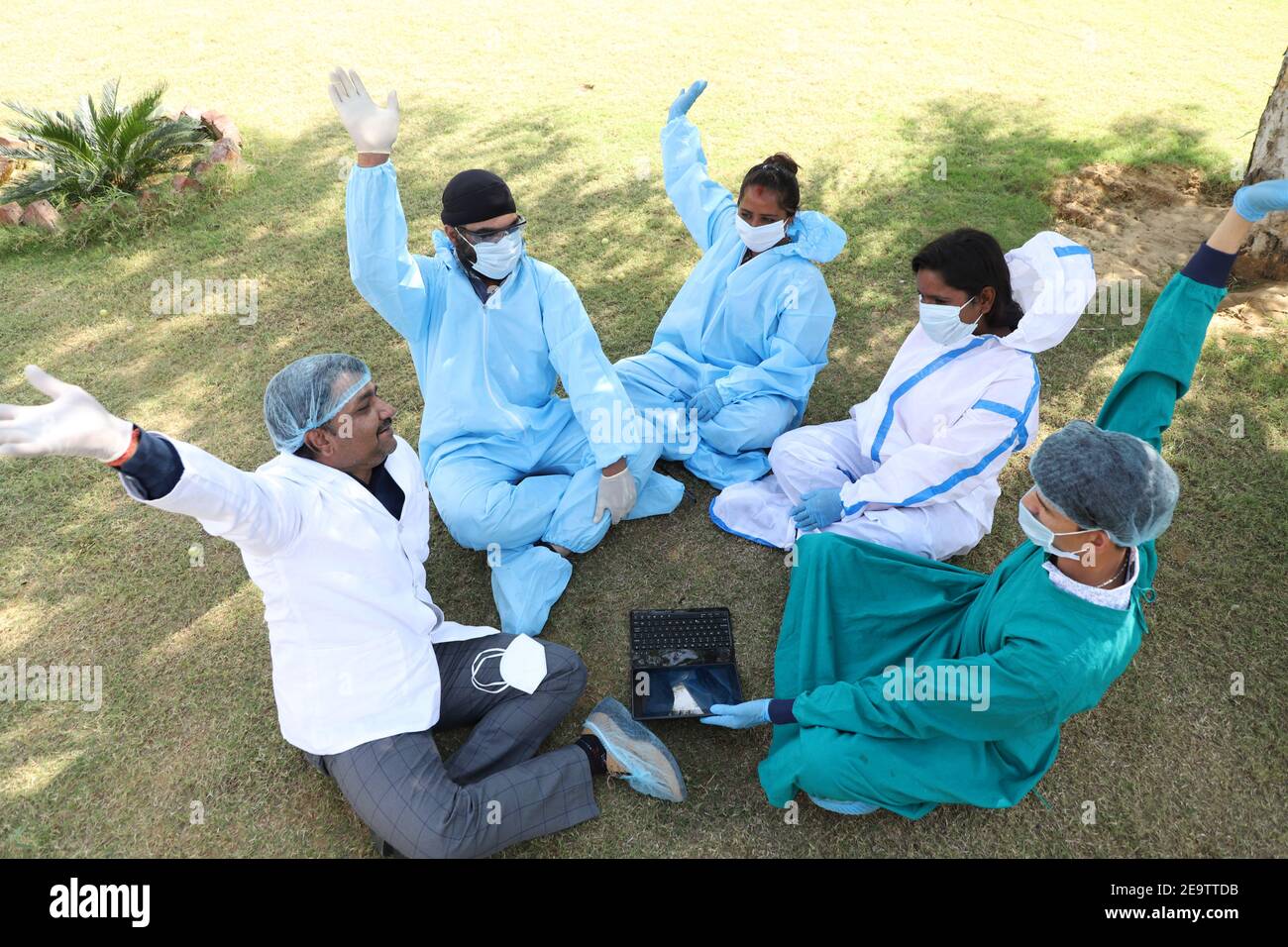 The Indian doctors high fiving each other while sitting on green grass ...
