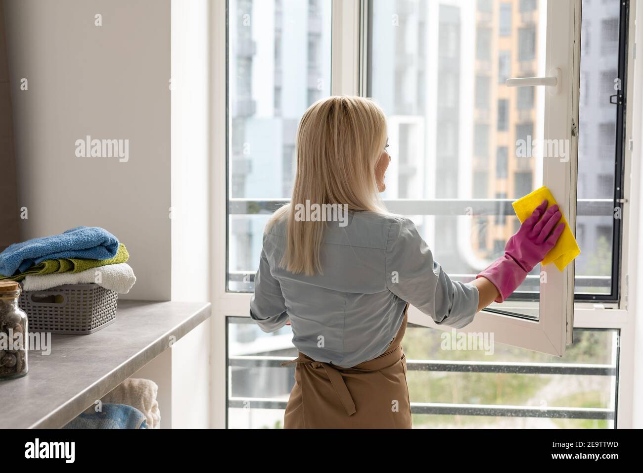 Smiling black woman cleaning windows with glass cleaner Stock Photo - Alamy