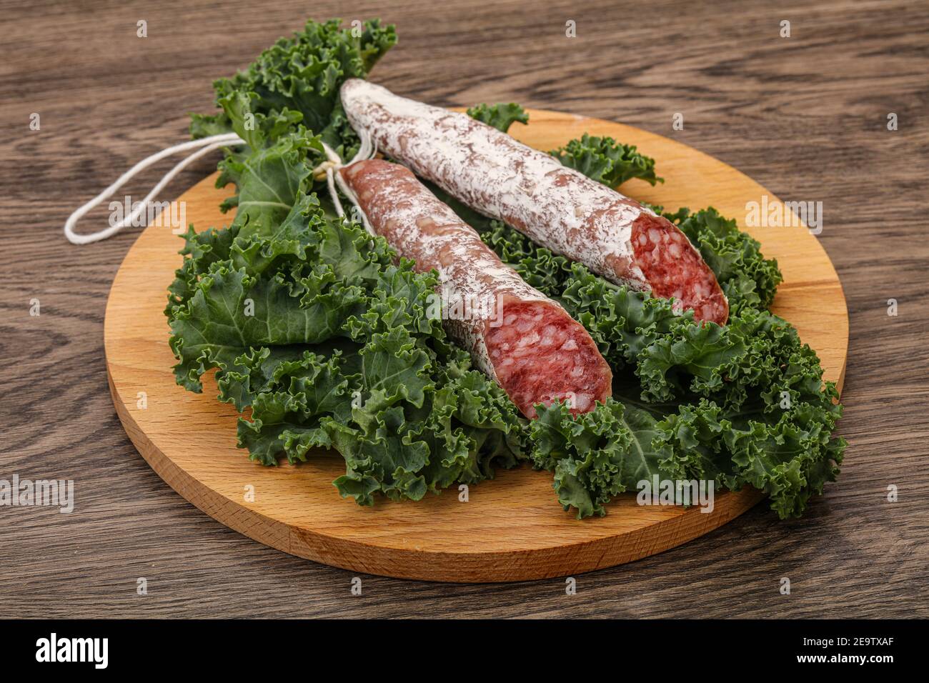 Spanish Fuet sausage with salad leaves over wooden background Stock ...