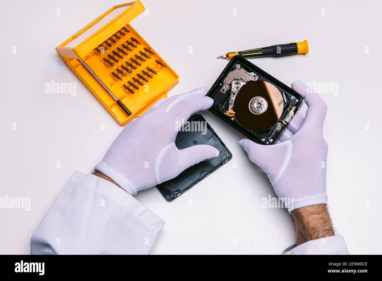 Hands of a technician with gloves repairing a hard drive. Technology ...