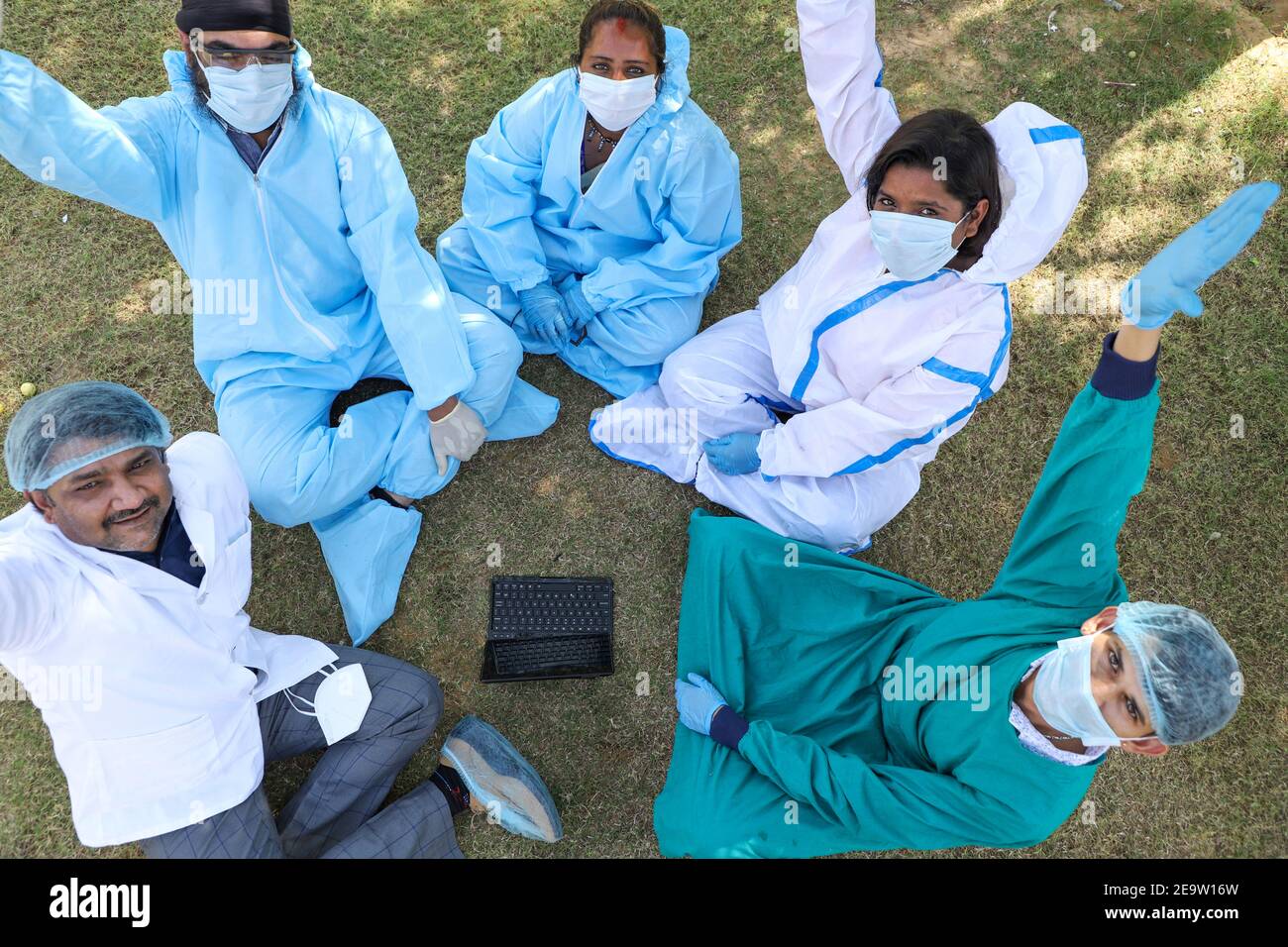The Indian doctors with raised hands sitting on green grass - teamwork ...